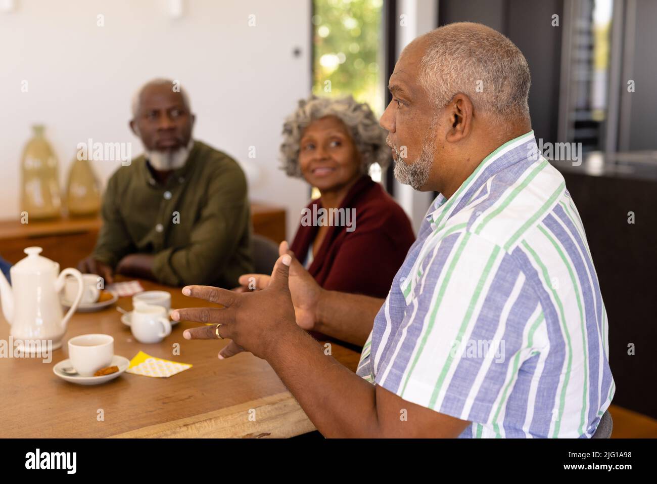 Multiracial senior man talking with friends while having coffee and ...