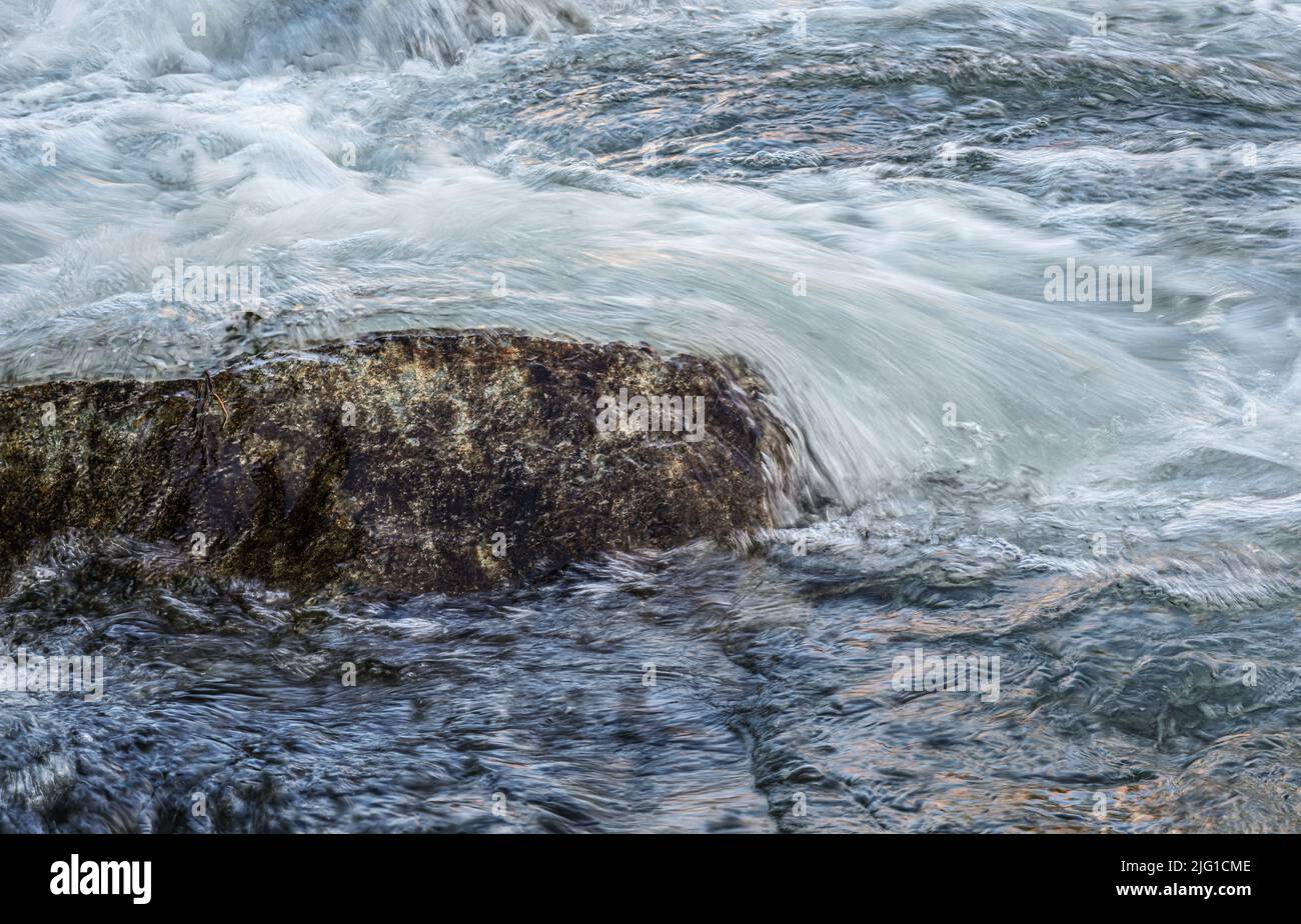 Rapid spring river flowing over rocks on sunny day, forming white water ...