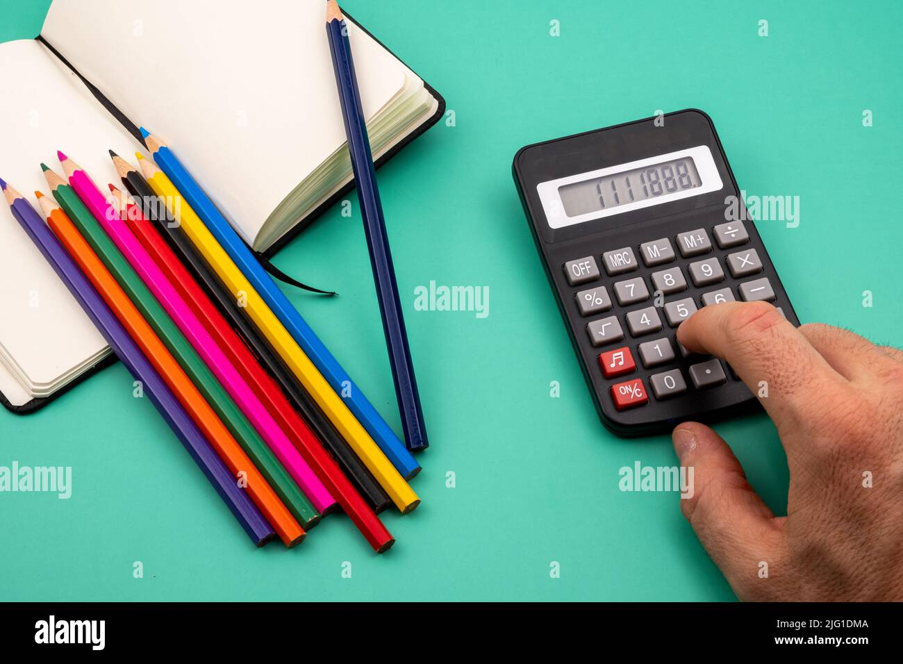 Top view of a hand pressing buttons on a calculator with a handful of ...