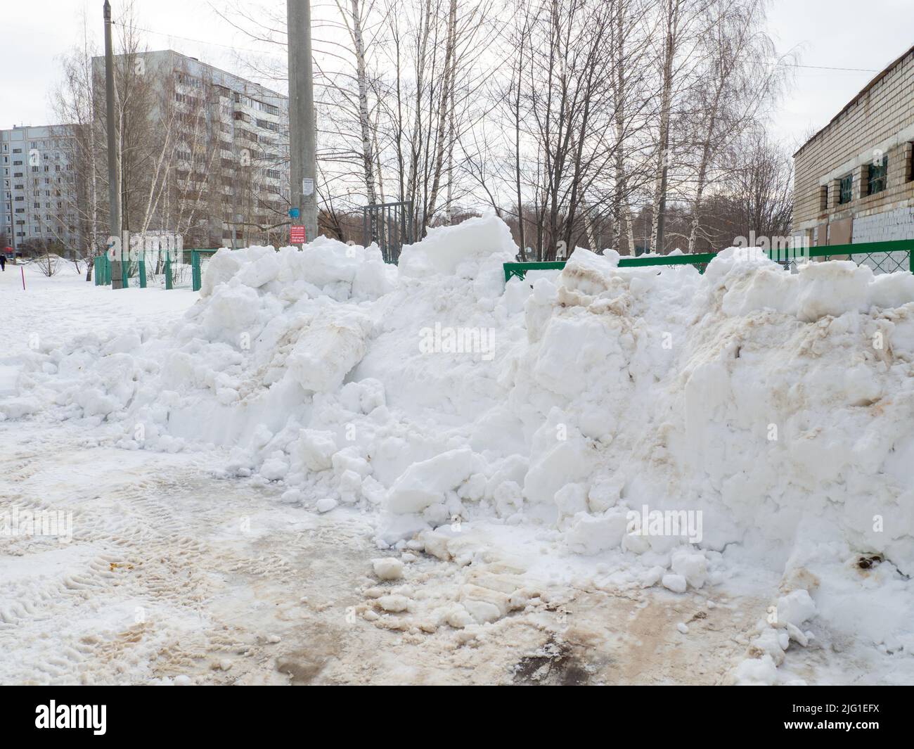 Street photo. Big snowdrifts in the city. The path after the passage of ...