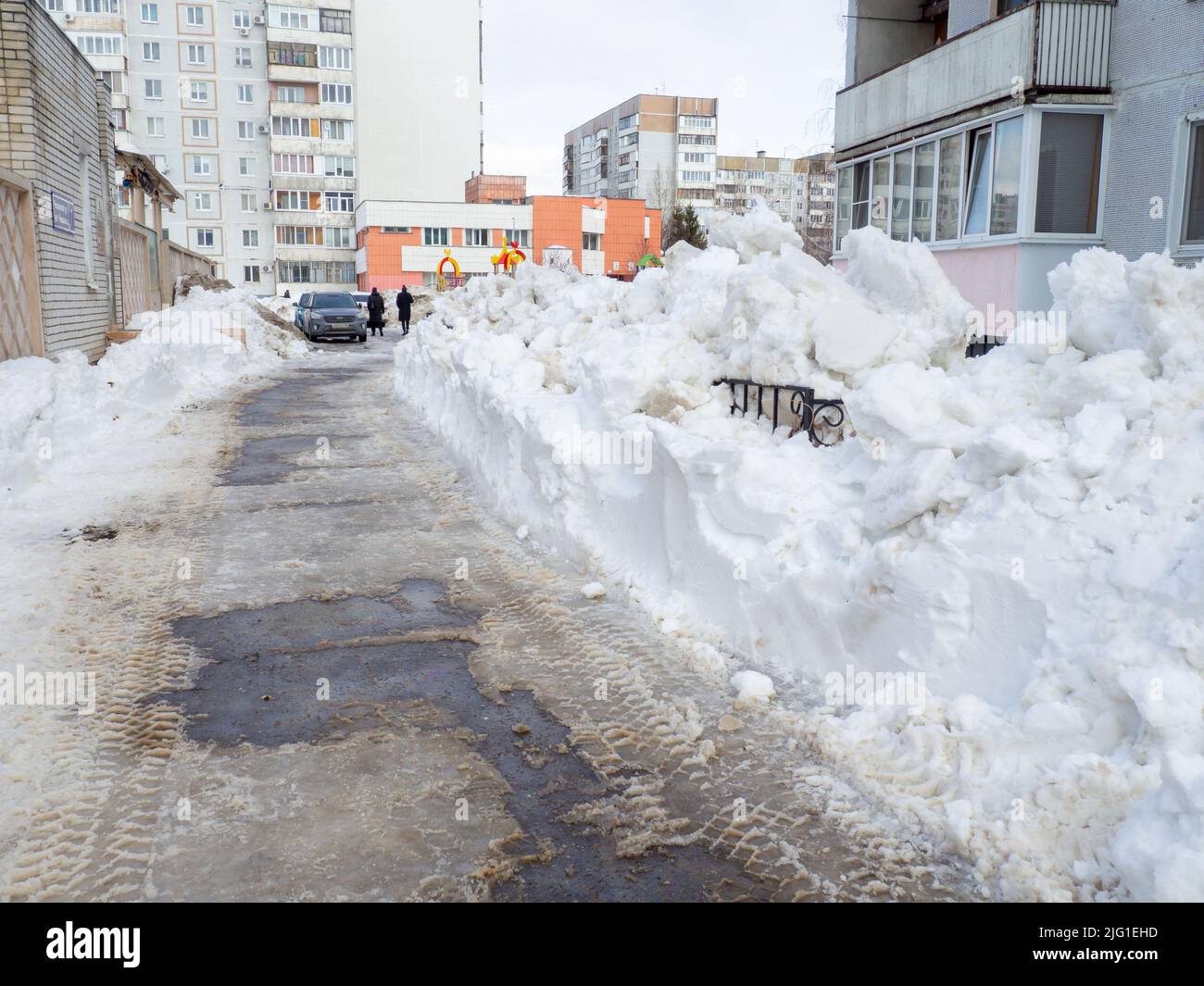 Street photo. Big snowdrifts in the city. The path after the passage of ...