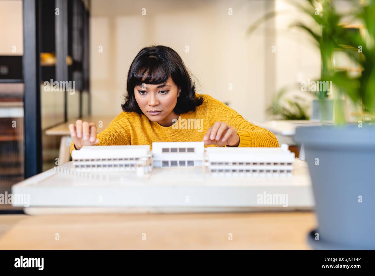 Biracial young female architect examining architectural model in ...