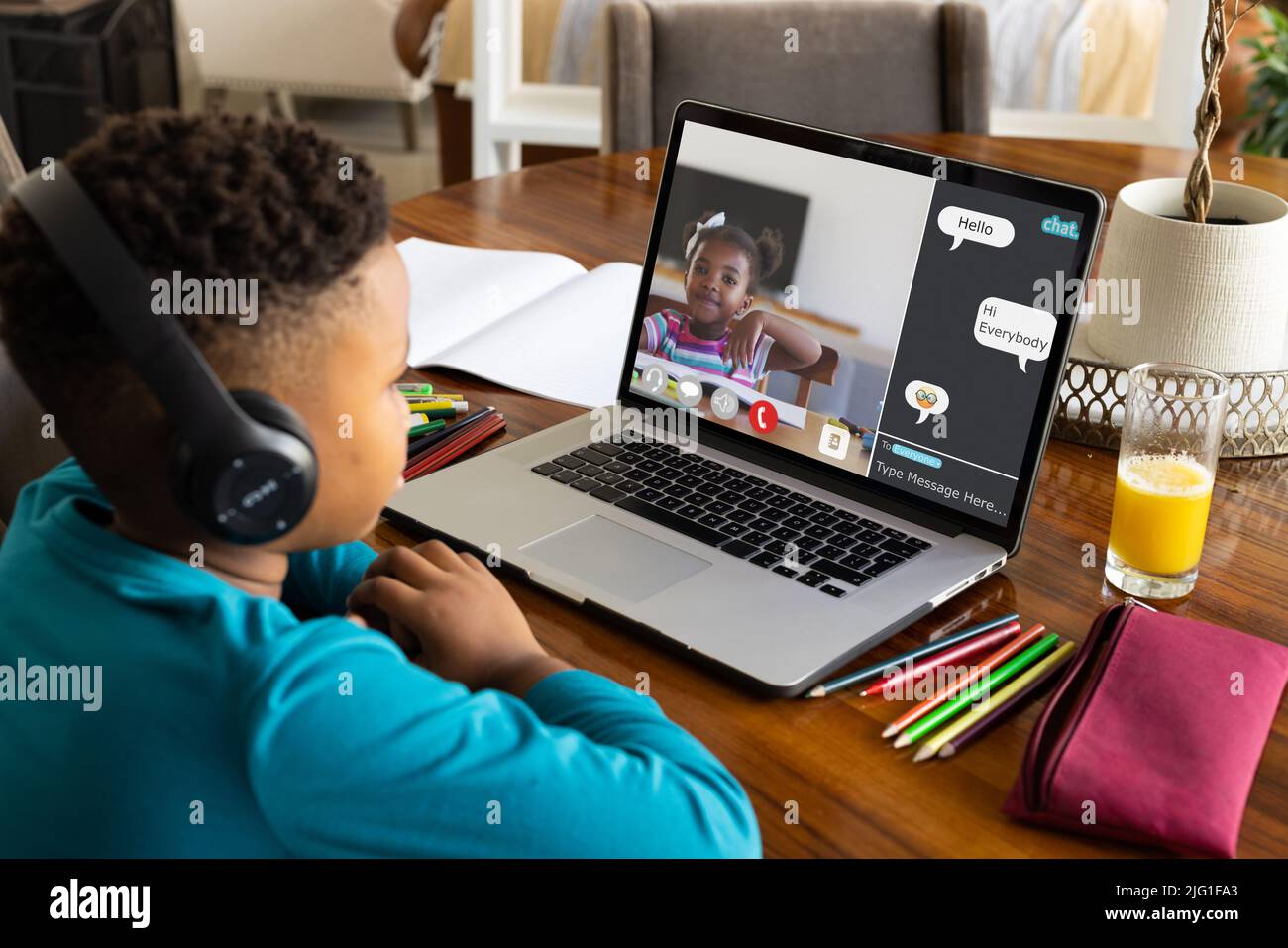 Biracial boy wearing headphones looking at laptop screen during online ...