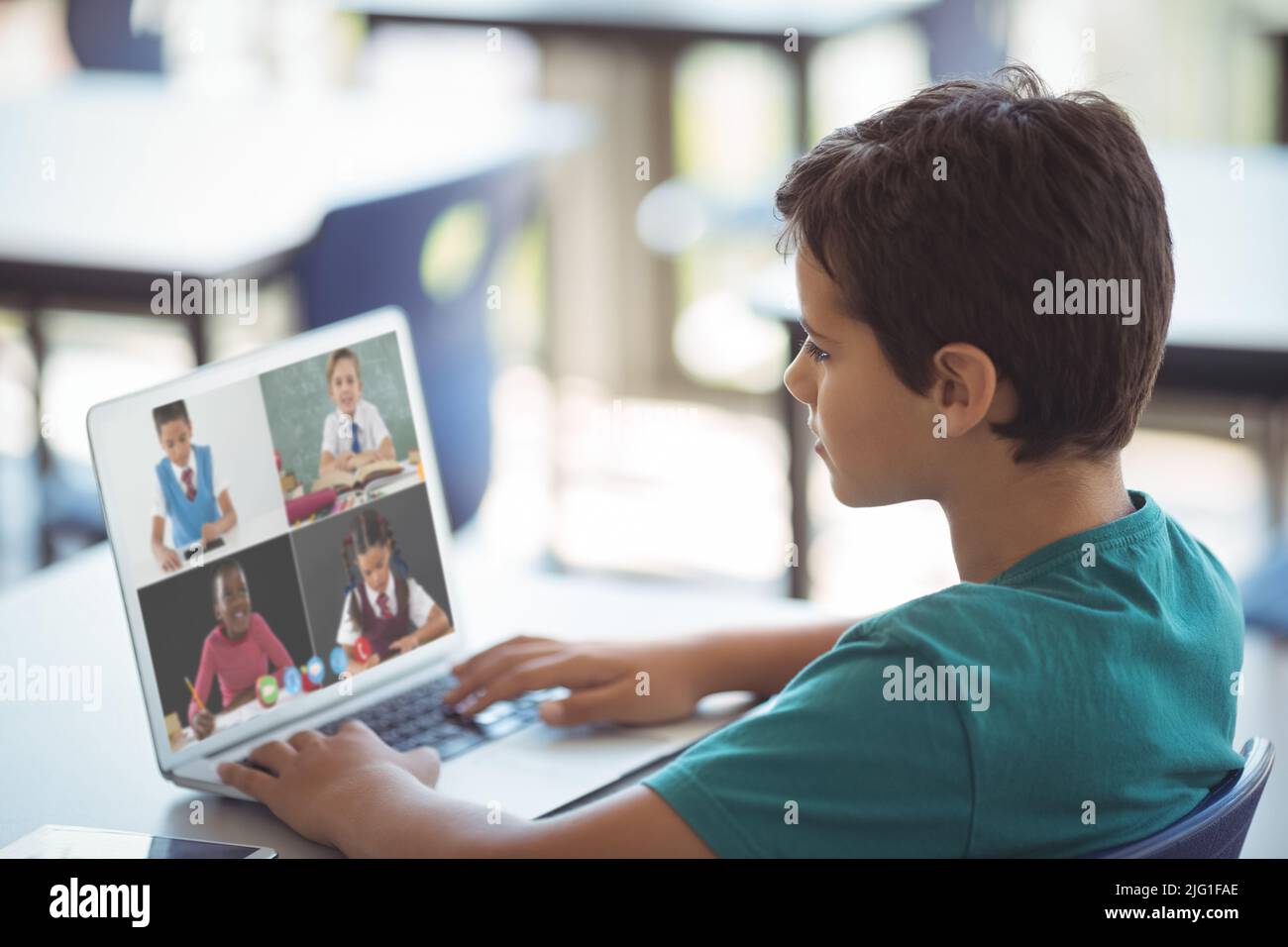 Side view of caucasian boy looking at screen with students on video ...