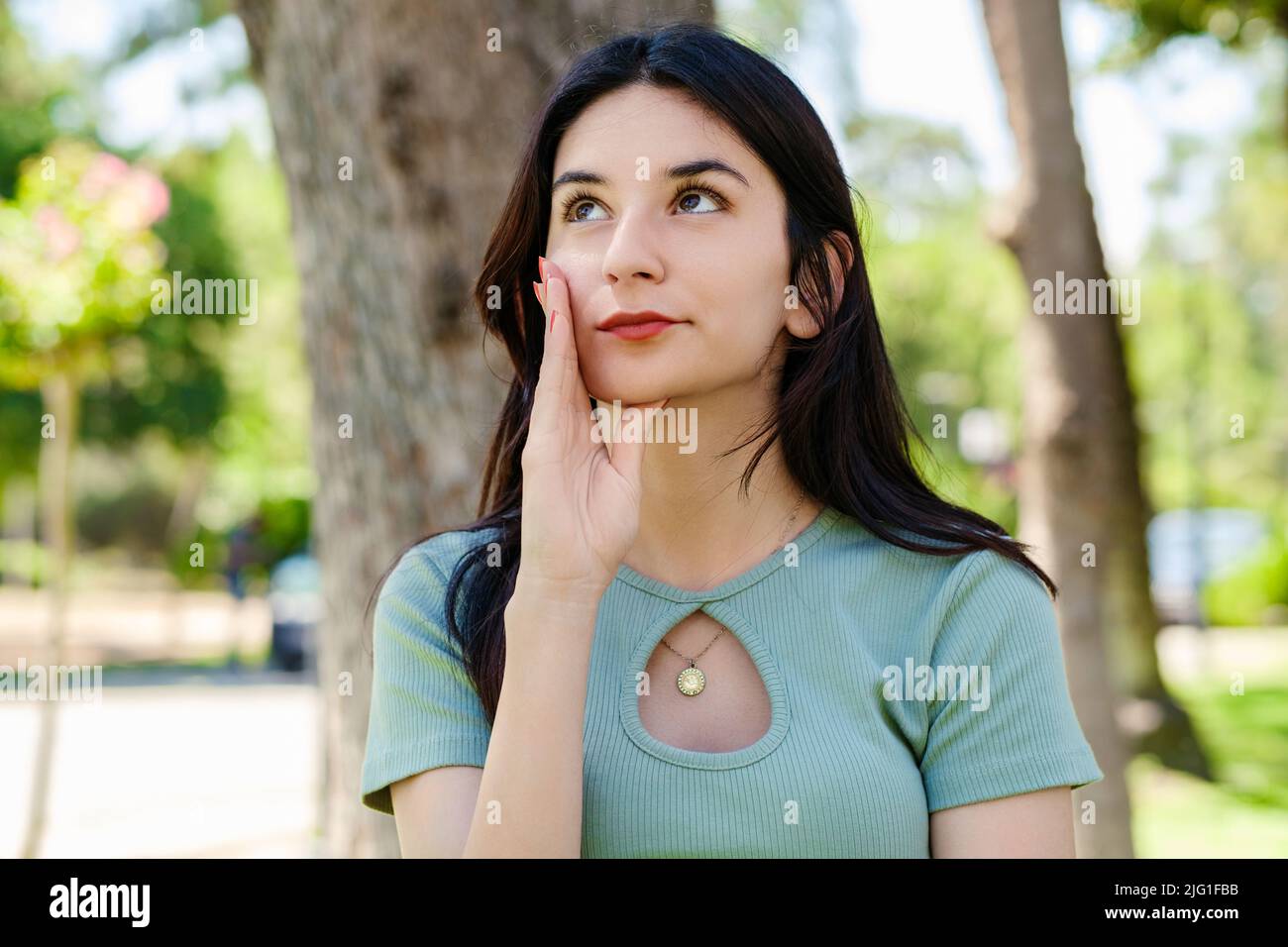Young beautiful woman wearing turquoise tee on city park, outdoors ...