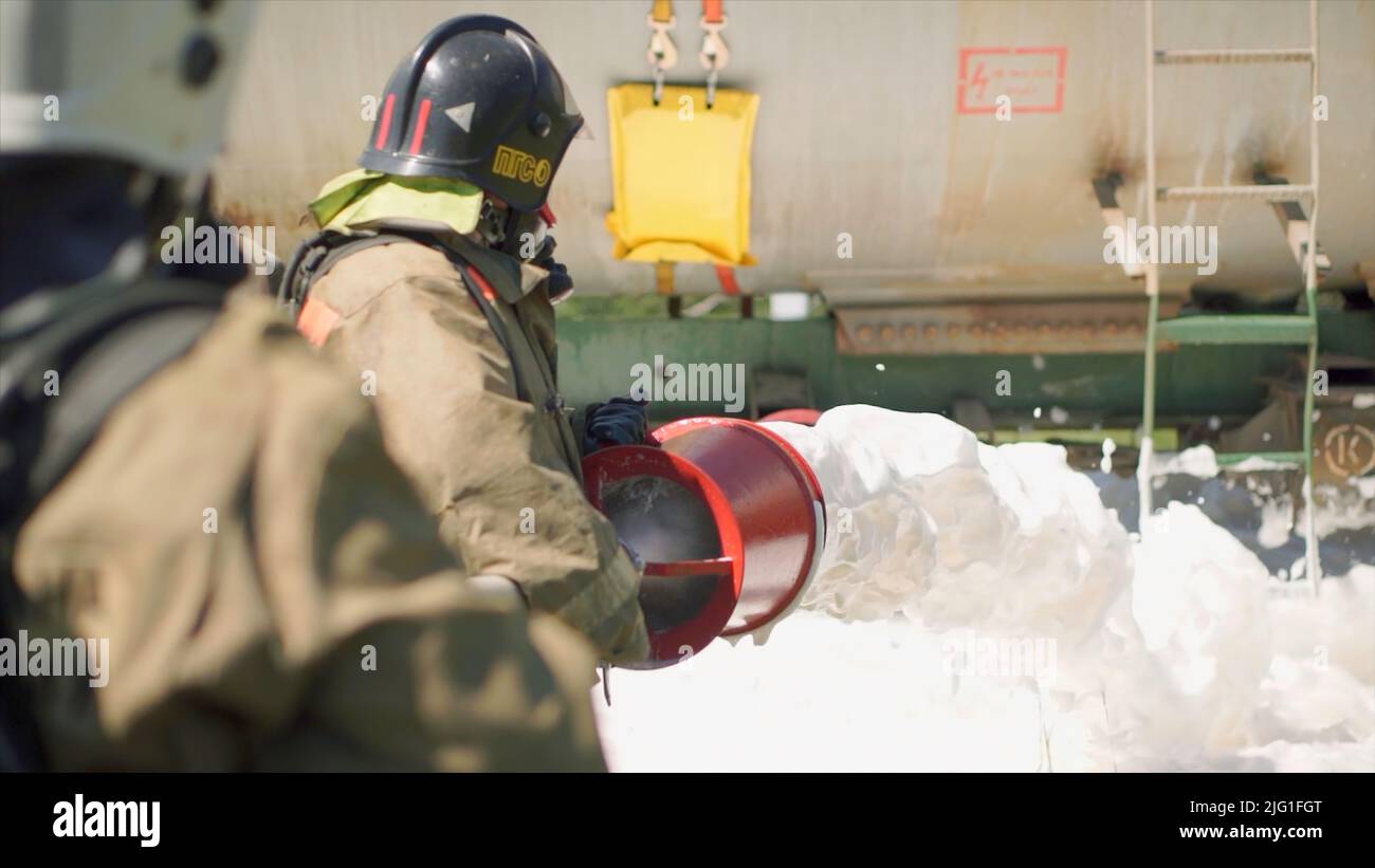 Firefighters pour liquid foam. Clip. Firefighters with large hose ...