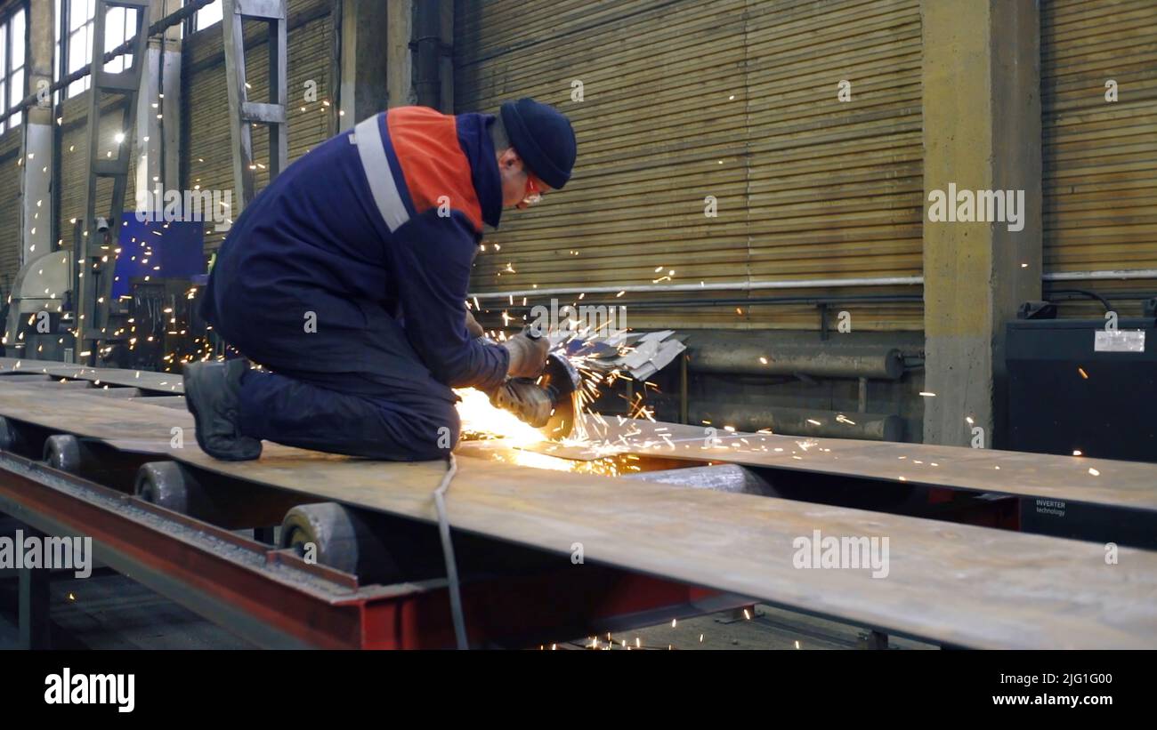 Blacksmith or welder technician grinding metal with flash of sparks ...