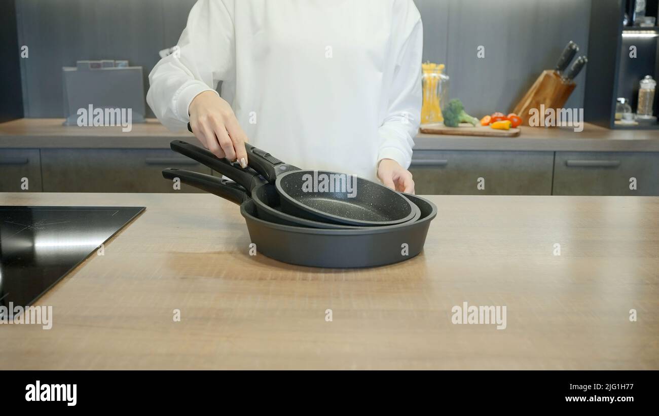 New set of frying pans demonstrated by a chef in white uniform. Action ...