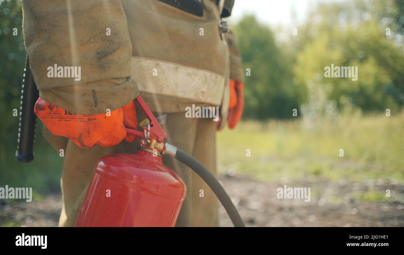 Close up side view of firefighter with a red fire extinguisher in a ...