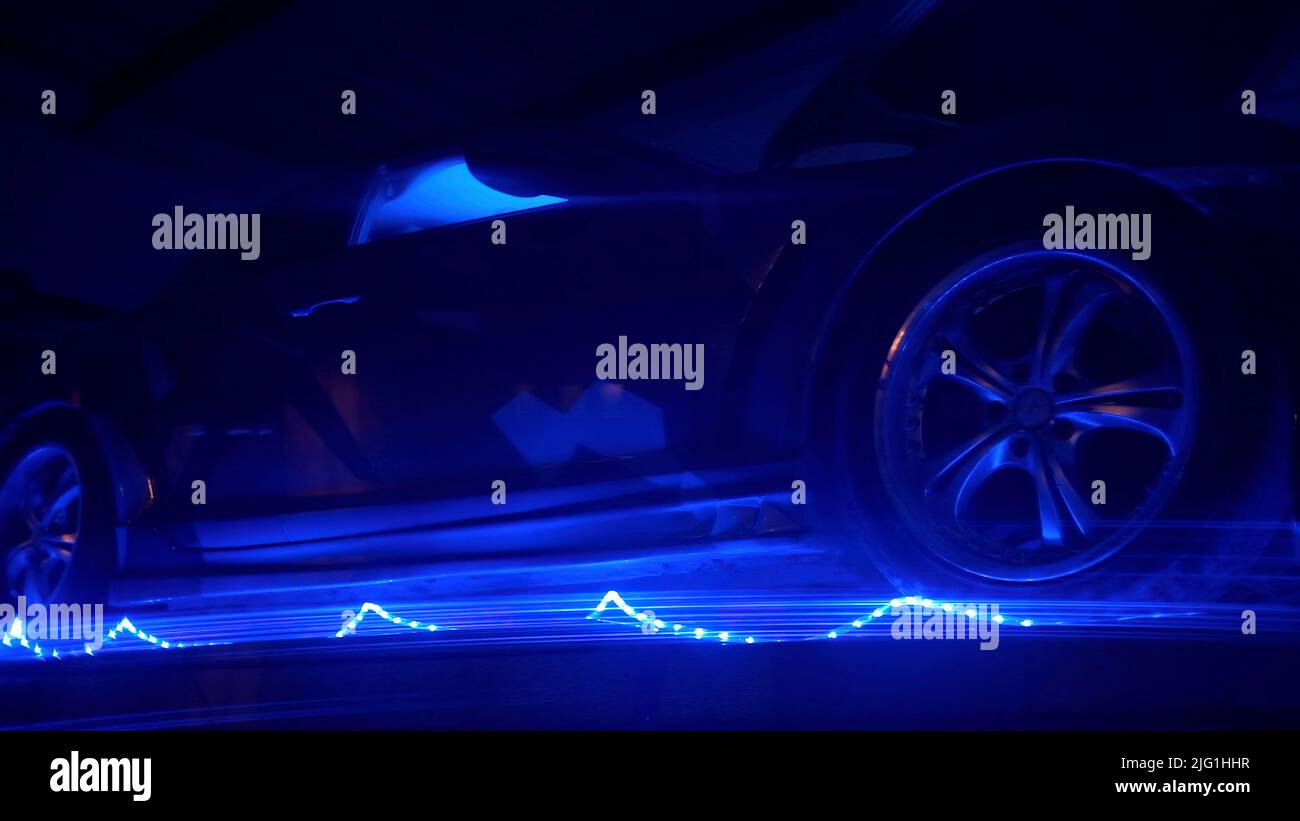 Bottom view of a modern car with neon light illumination in a dark ...