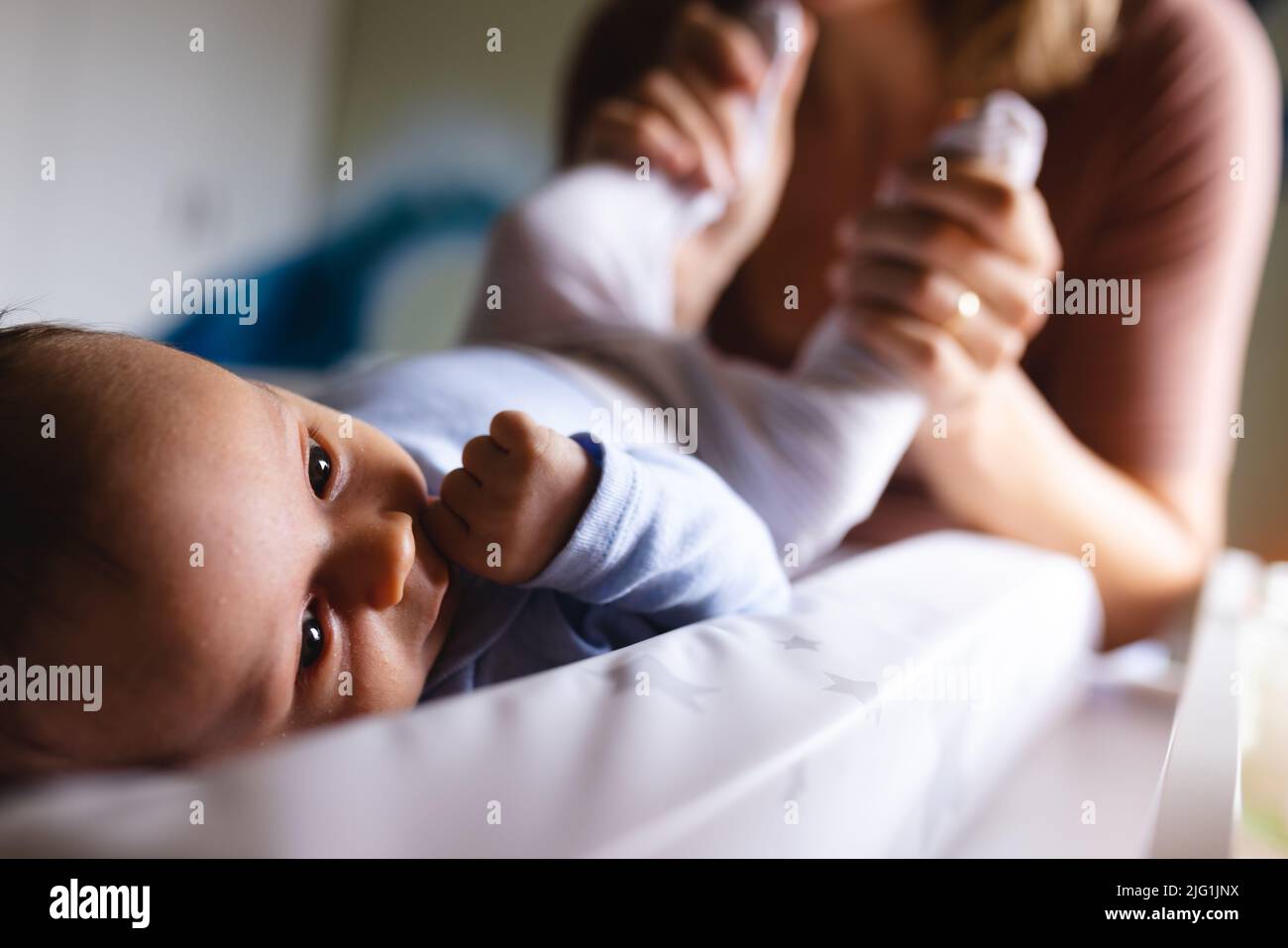 Cute newborn baby on nappy changing table held by mid adult caucasian ...