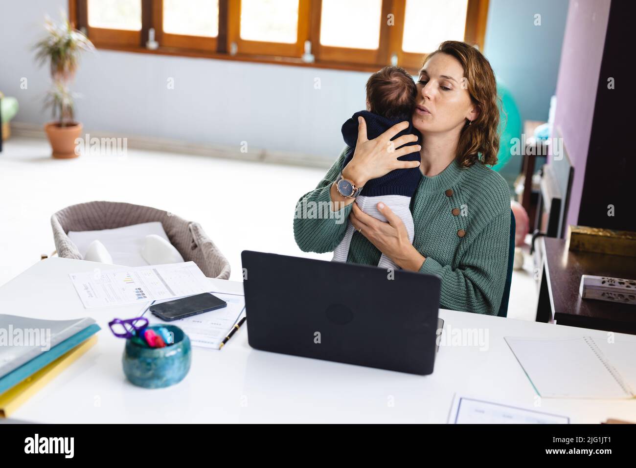 Mid adult caucasian mother pacifying and carrying newborn baby while ...