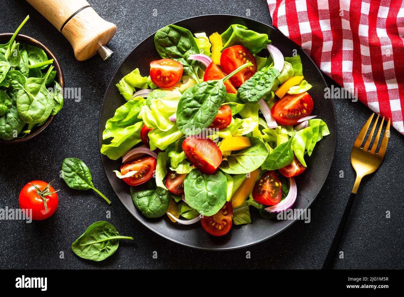 Green salad with fresh vegetables and green leaves at black background ...