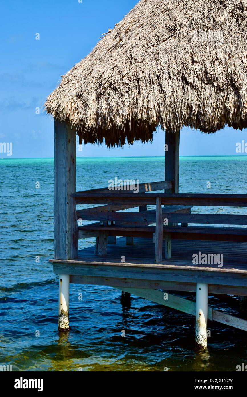 A palapa with a seating area over the water on Ambergris Caye, Belize ...