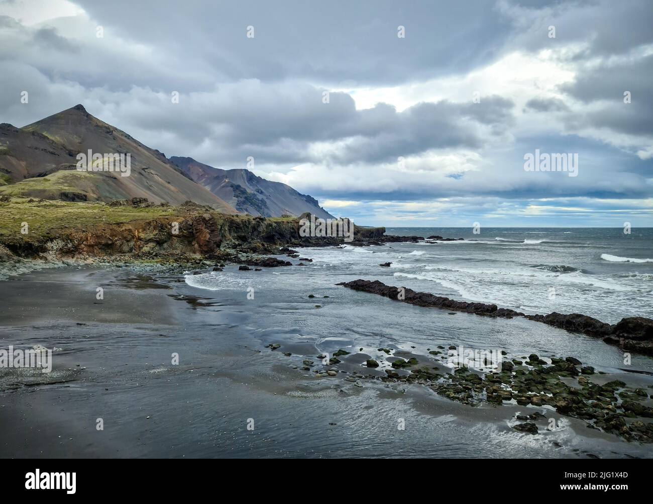 A rocky beach with bergs on Iceland in strong winds with powerful surf ...