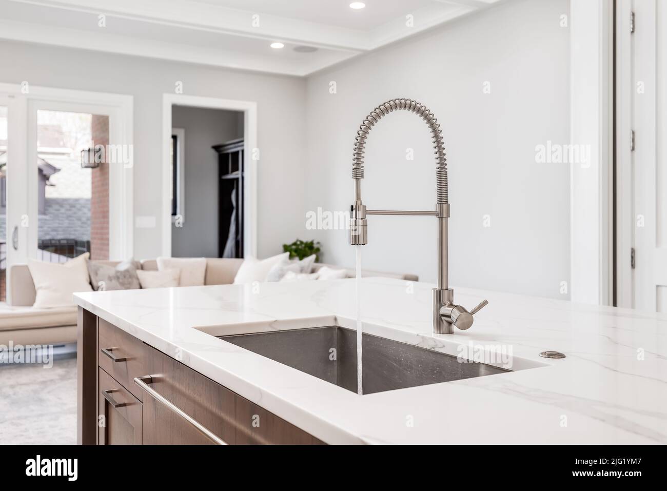 A kitchen faucet detail with a wood and marble countertop island and a ...