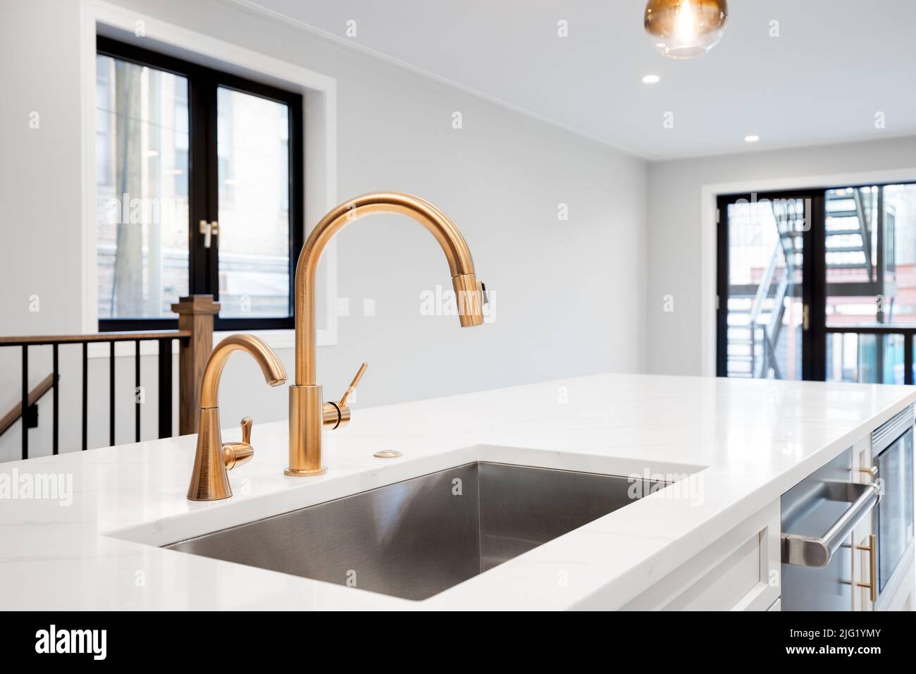 A gold kitchen faucet detail shot with an all white kitchen, a gold ...