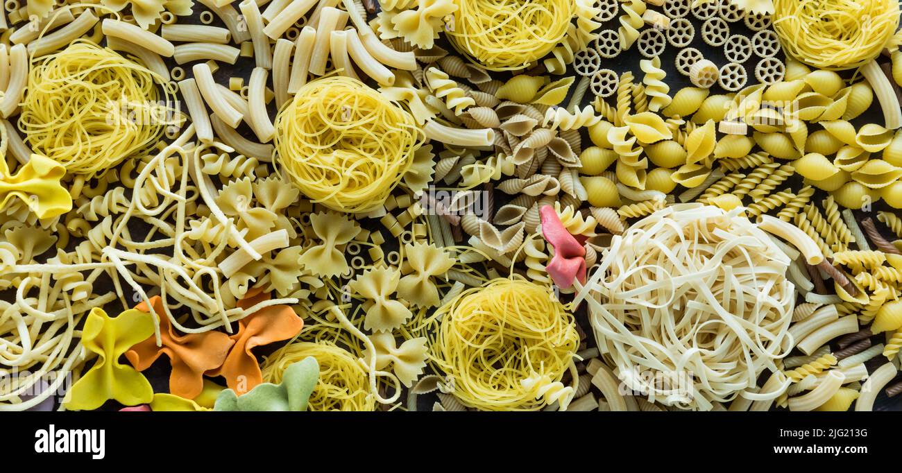 Narrow top down view of various shapes of dry pasta scattered about ...