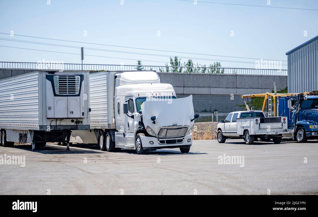 White broken big rig semi truck tractor with open hood and refrigerator ...