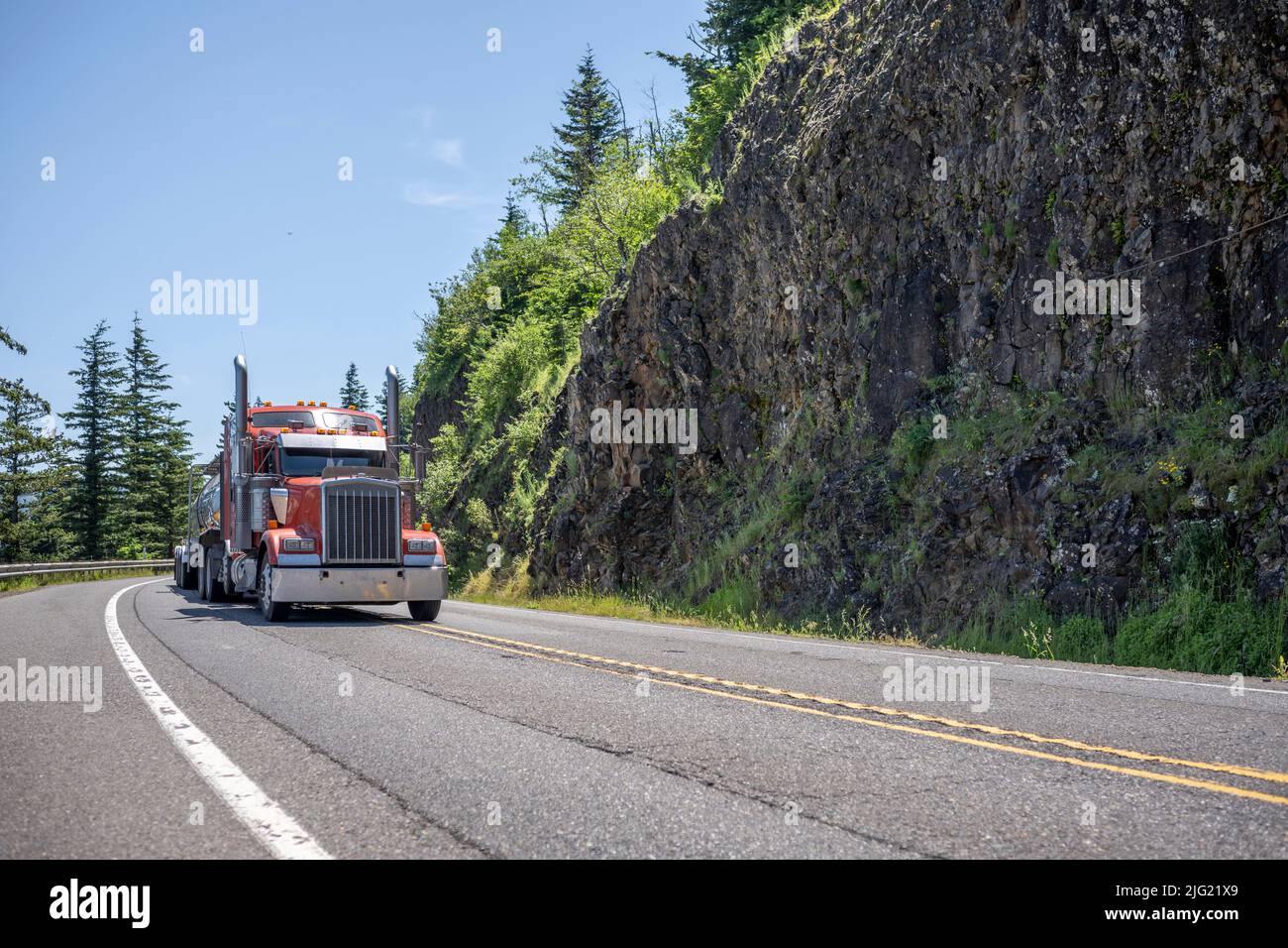 Classic orange American big rig semi truck tractor transporting liquid ...