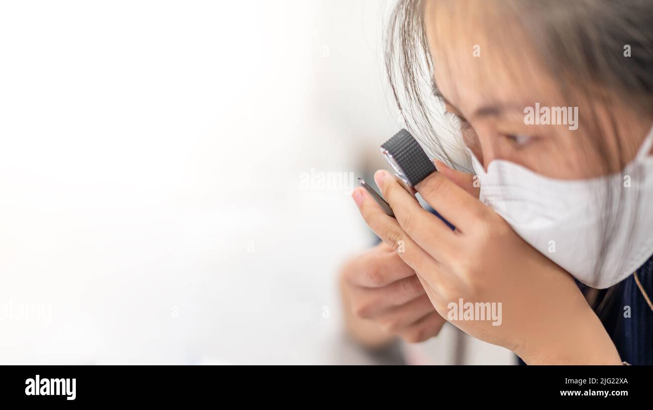 Female using loupe and tweezer while examing the precious stone as the ...