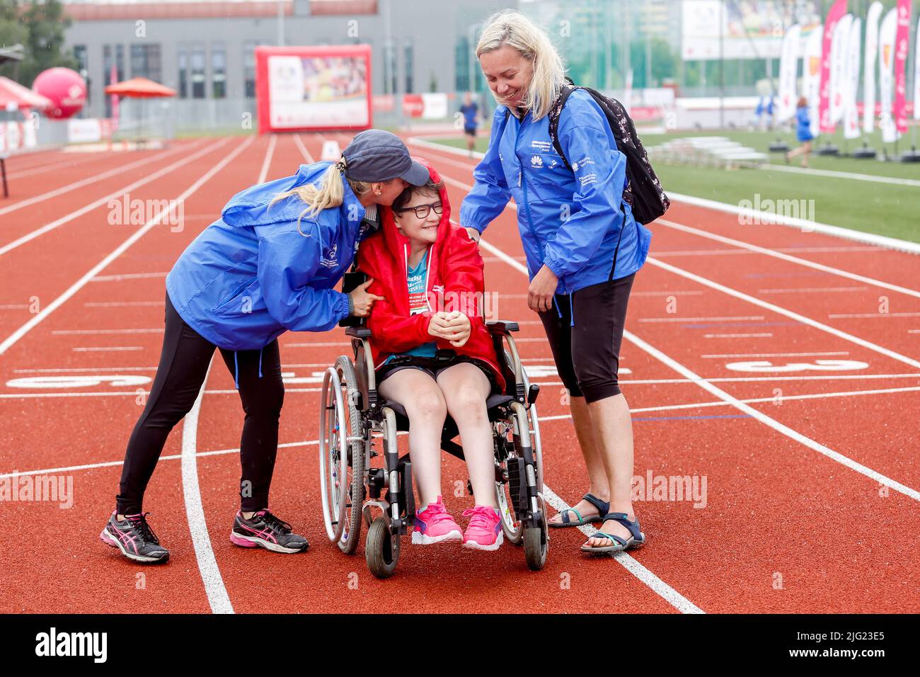 Volunteers congratulate an athlete from Poland after a 50 meter race ...