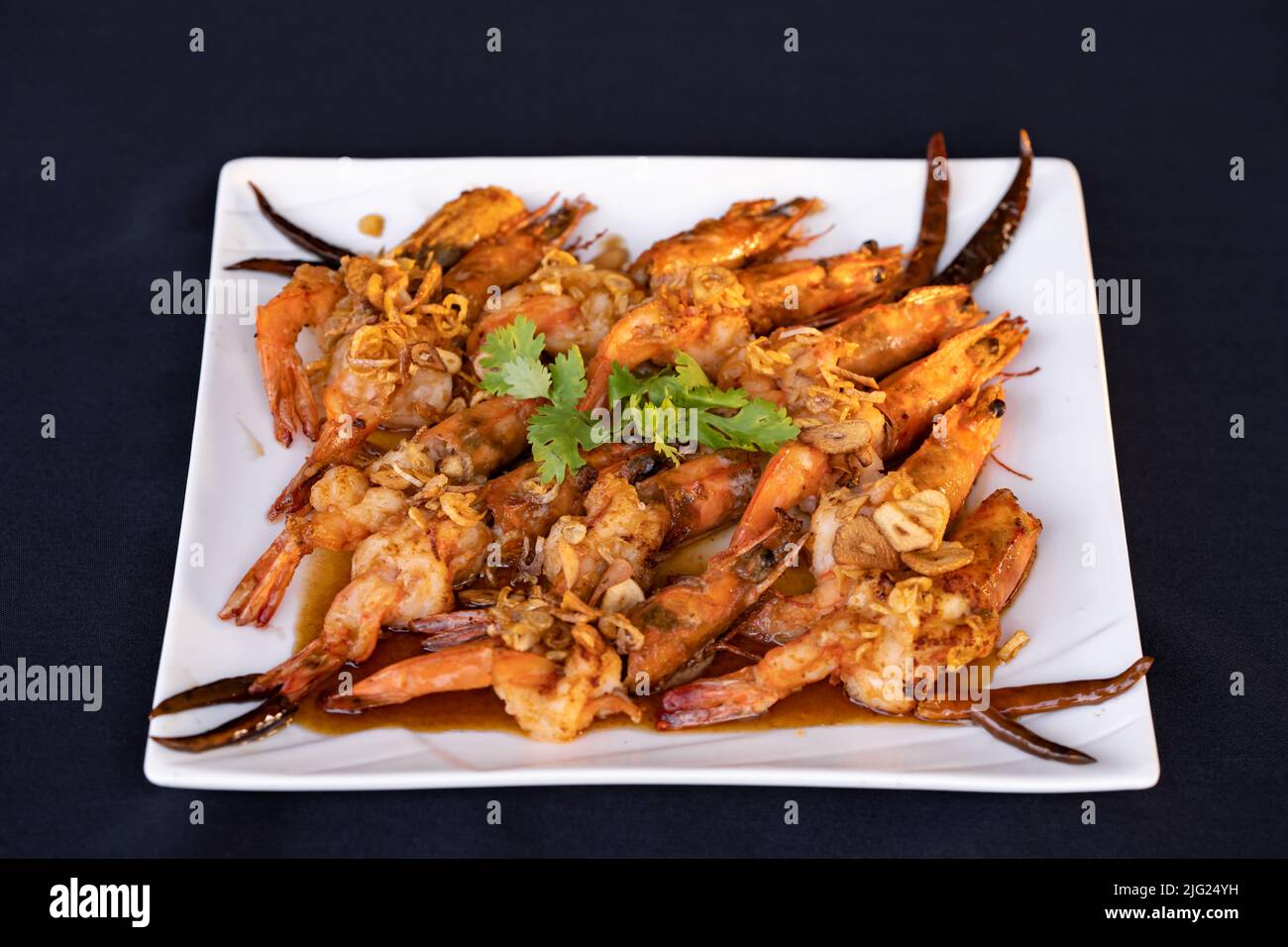 Crispy prawns in tamarind sauce in white square dish, sprinkle with ...