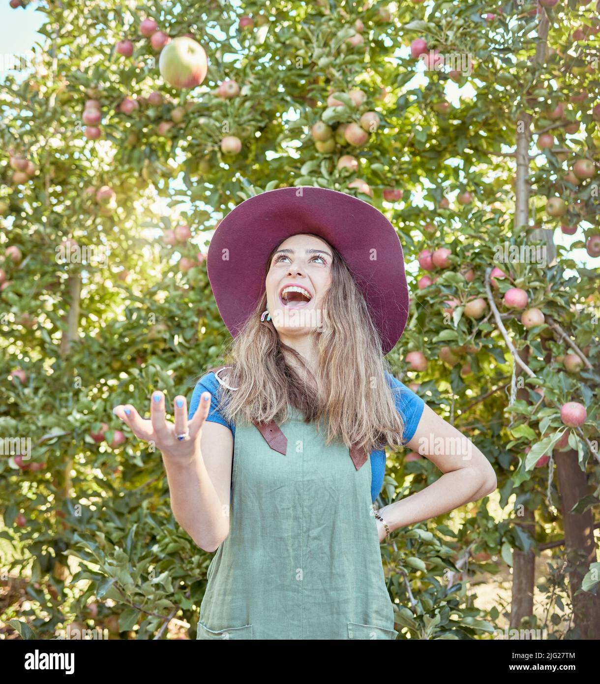Beautiful young female farmer throwing an apple on a farm during ...