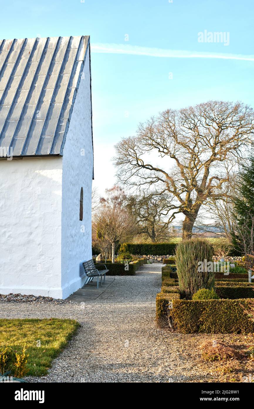Classic old white farm house or church with a beautiful green garden in ...