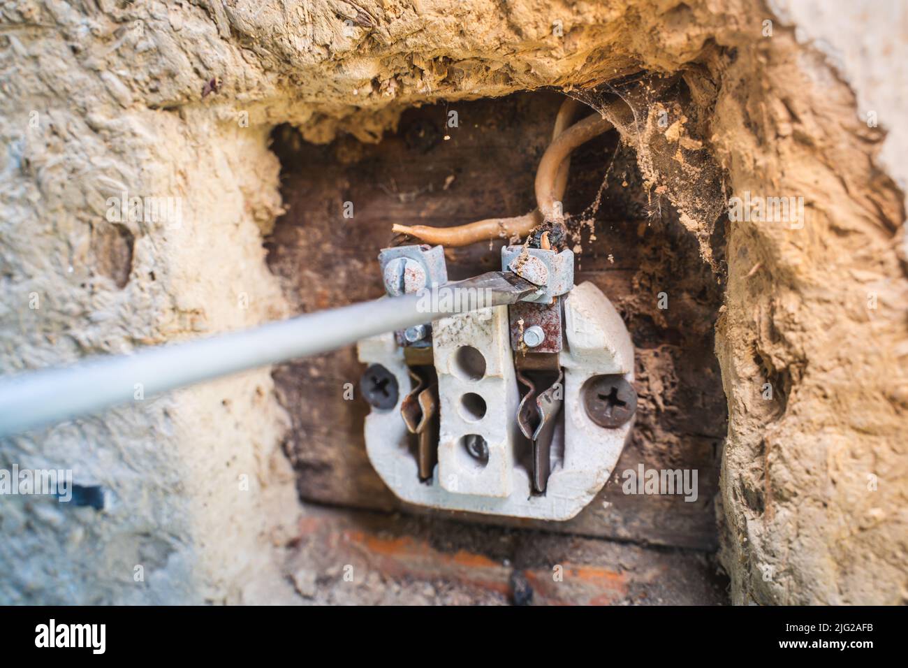 Unscrew the wire clamp in an old outlet in a clay wall close -up Stock ...