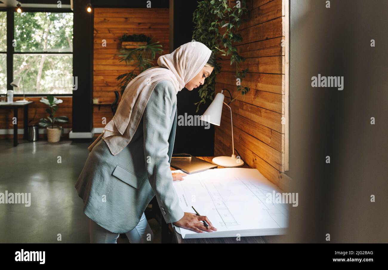 Thoughtful Muslim designer working with drawings in a modern office. Creative young architect ...