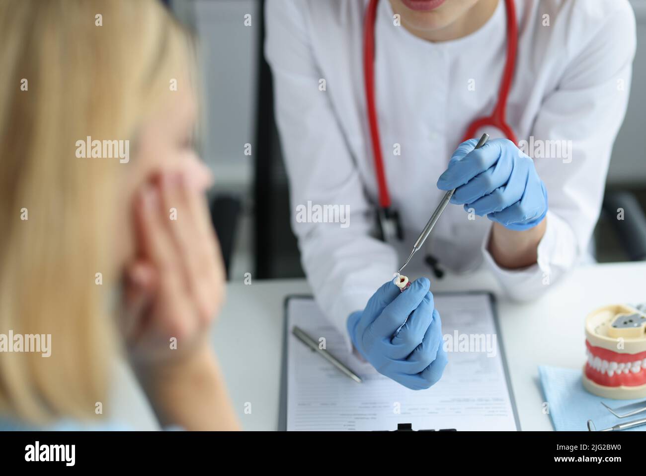Female dentist showing patient tooth with hole inside and caries Stock ...