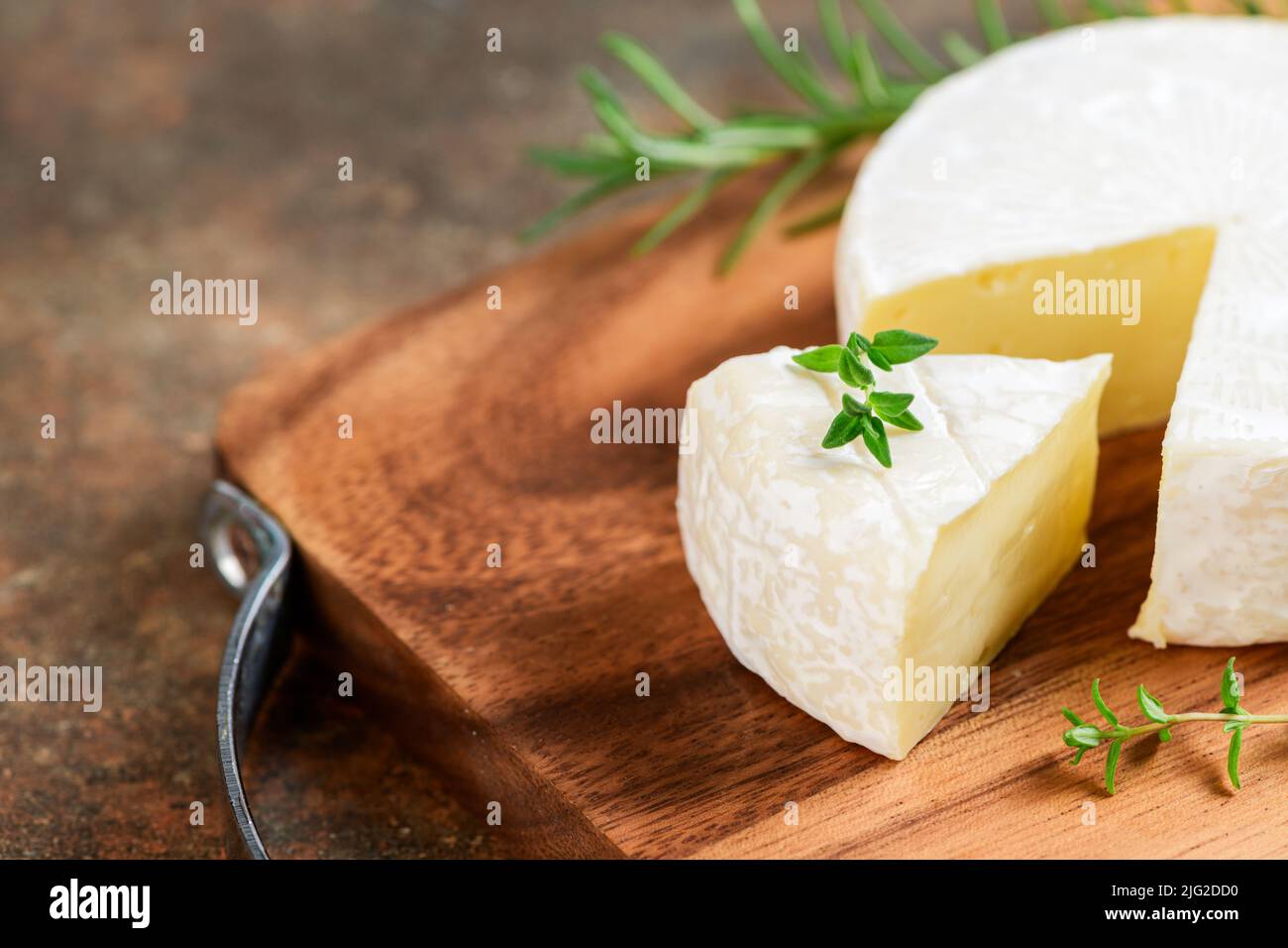 Sliced Camembert Cheese with thyme on wood plate. Camembert is a moist ...