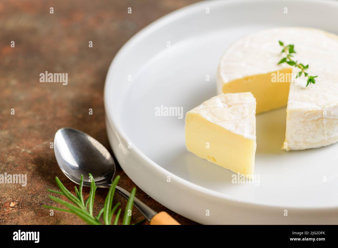 Sliced Camembert Cheese in white dish with spoon on table.Camembert is ...