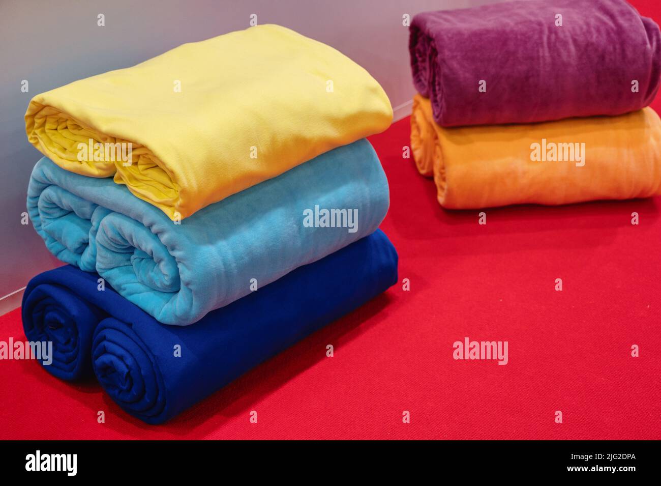 Rolled clothes fabrics samples lie on red table in hall Stock Photo - Alamy