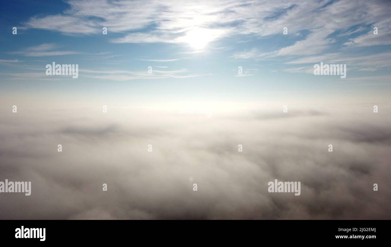 Aerial drone view flight over fog and under clouds with shining sun shining. Fly through clouds ...