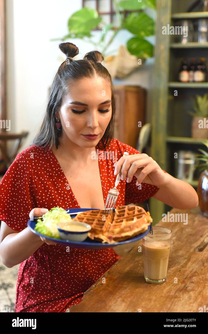 Young woman eating waffles in a coffee shop Stock Photo - Alamy