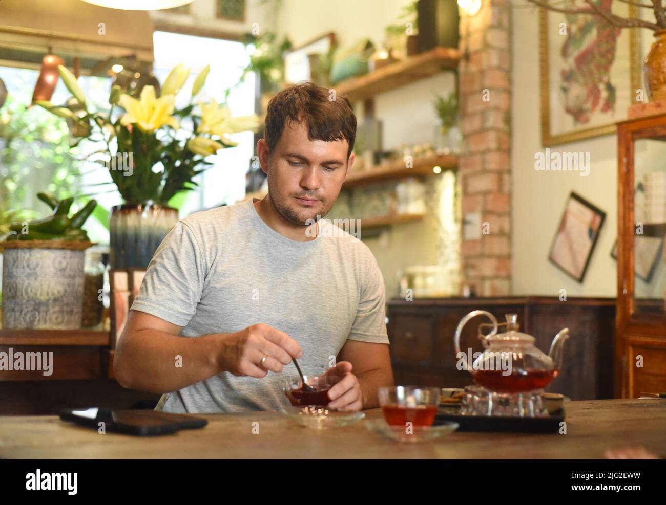 Young man eating homemade jam and tea in cafe Stock Photo - Alamy