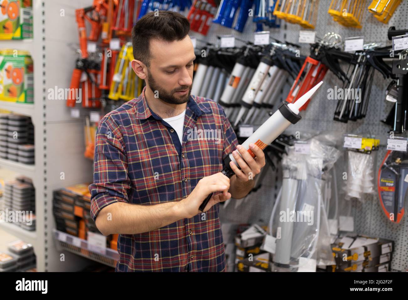 a man in a hardware store chooses a caulk gun Stock Photo - Alamy