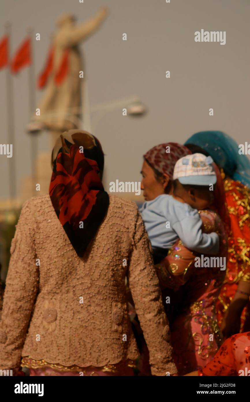 Uyghur women walking past Mao Ze Dong statue in Kashgar, Xinjiang Stock ...