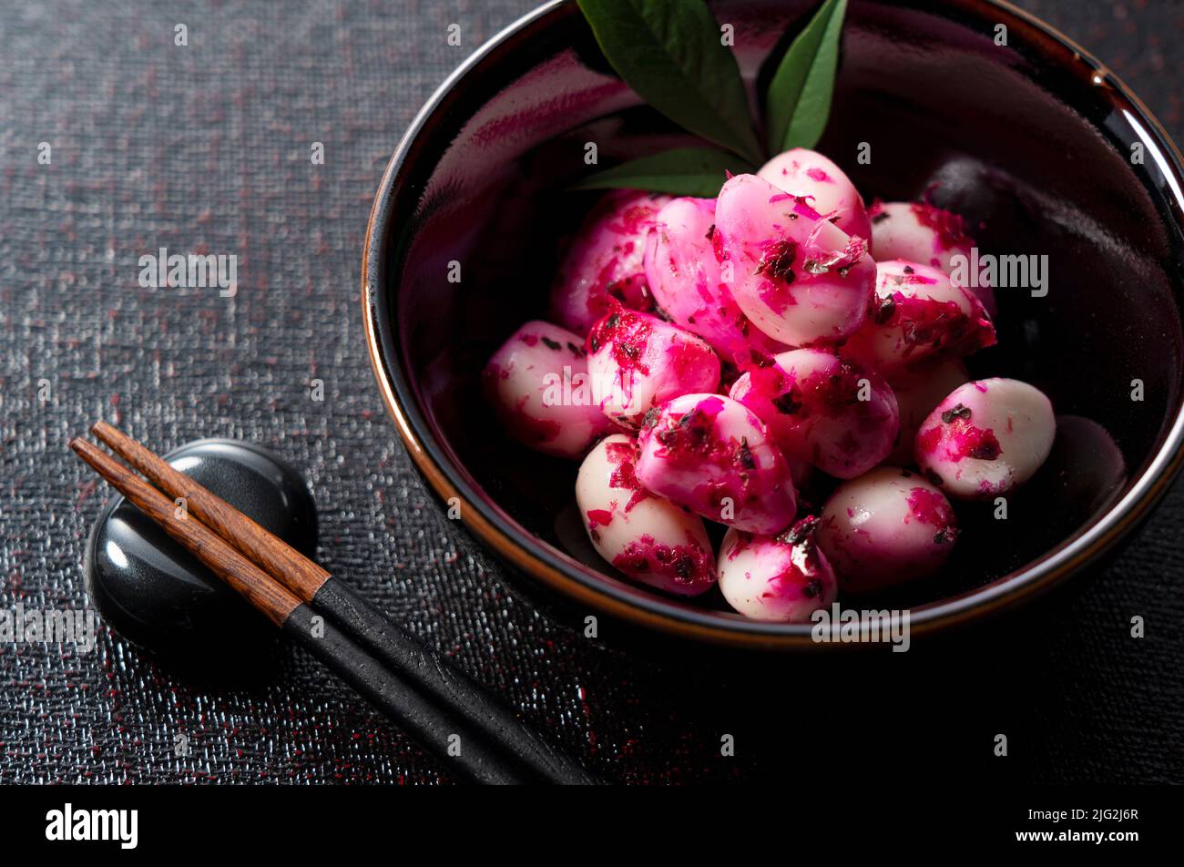 Pickled shiso bonito garlic on a plate placed on a black background ...