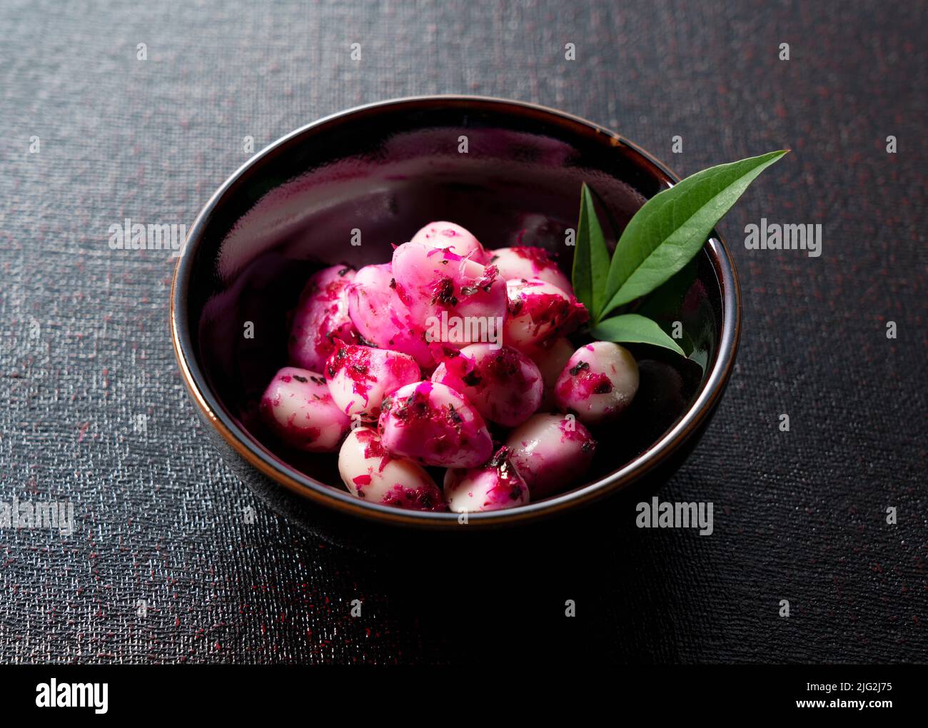Pickled shiso bonito garlic on a plate placed on a black background ...