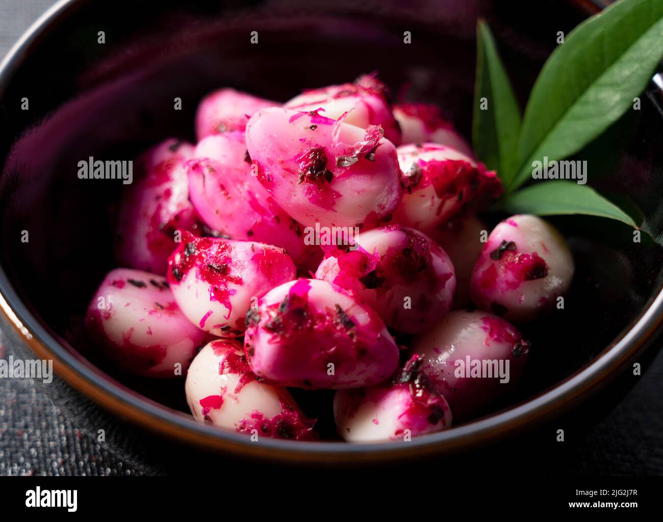 Pickled shiso bonito garlic on a plate placed on a black background ...