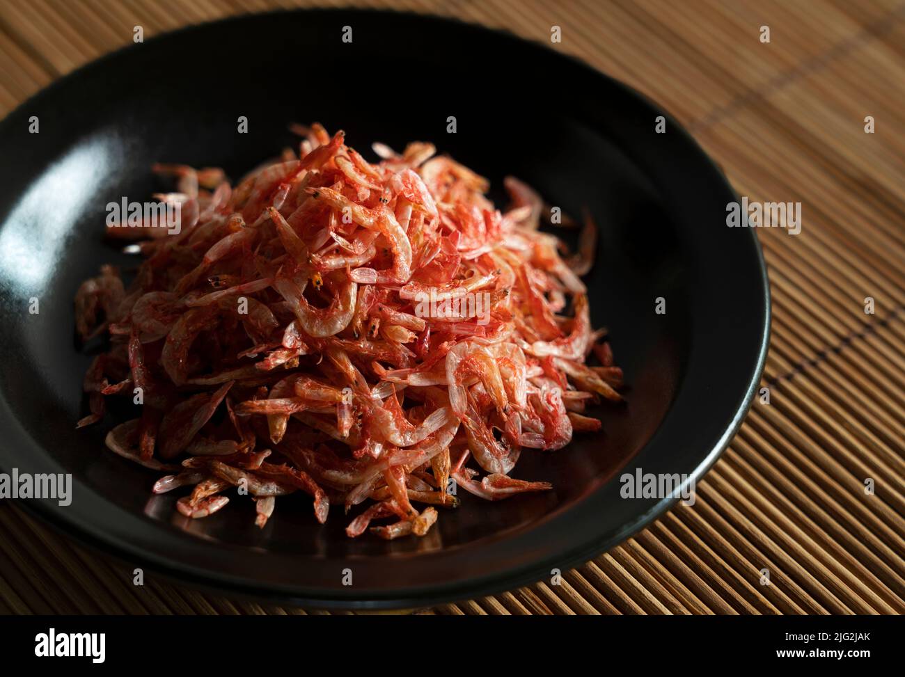 Dried sakura shrimps on a plate placed on a bamboo luncheon mat. The ...