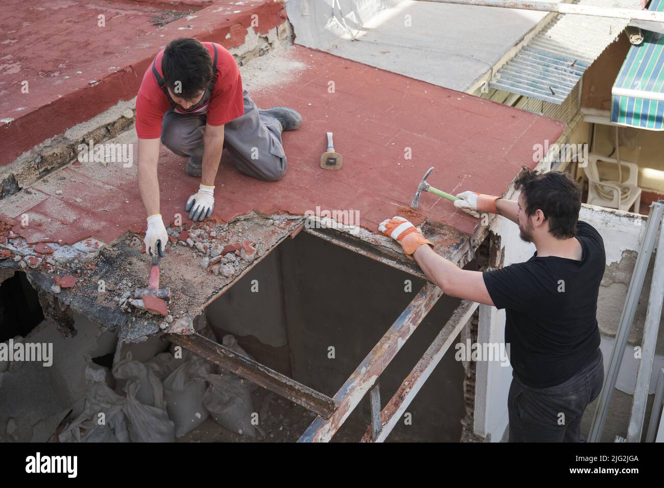 Two workers pulling apart the ceiling of a house down Stock Photo - Alamy