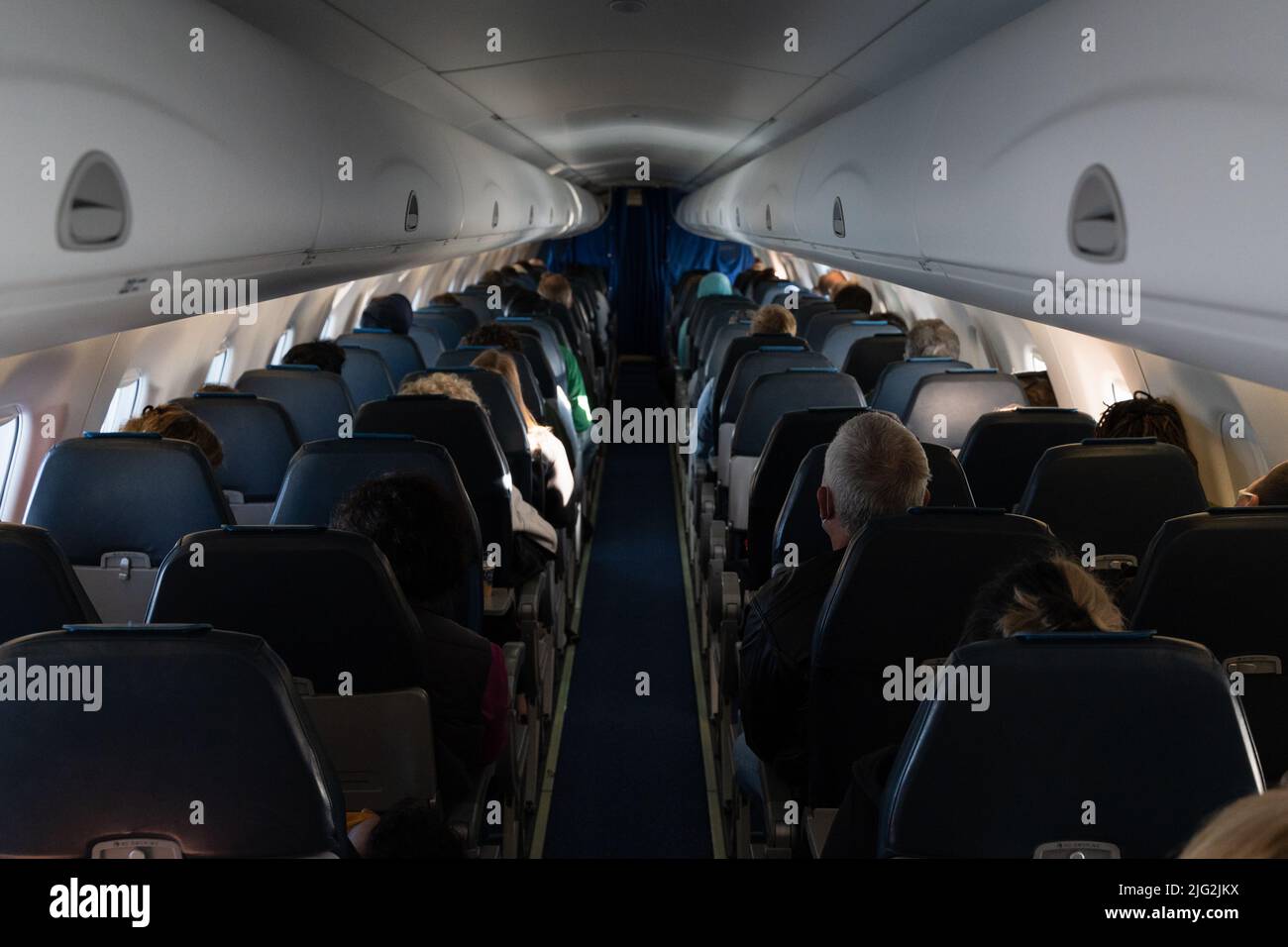 Interior of airplane passengers cabin and aisle view from back. People ...