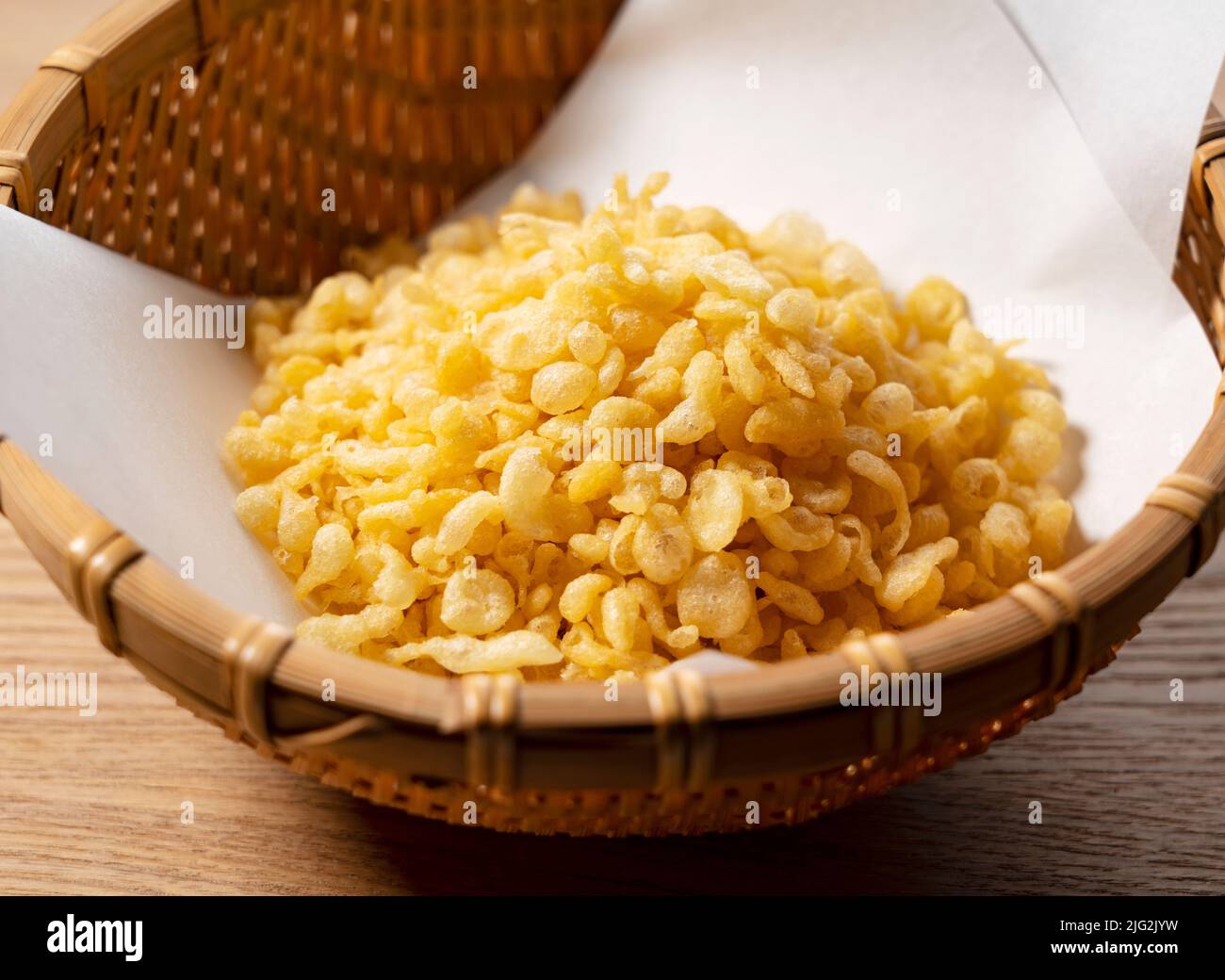 Tenkasu served in a colander placed against a wooden background. Image ...