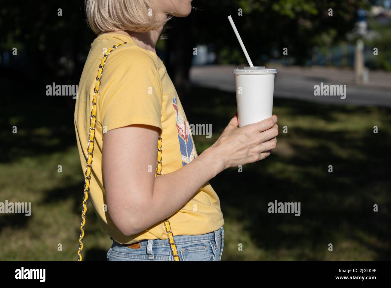 woman's hand holding a white paper glass with a straw Stock Photo - Alamy