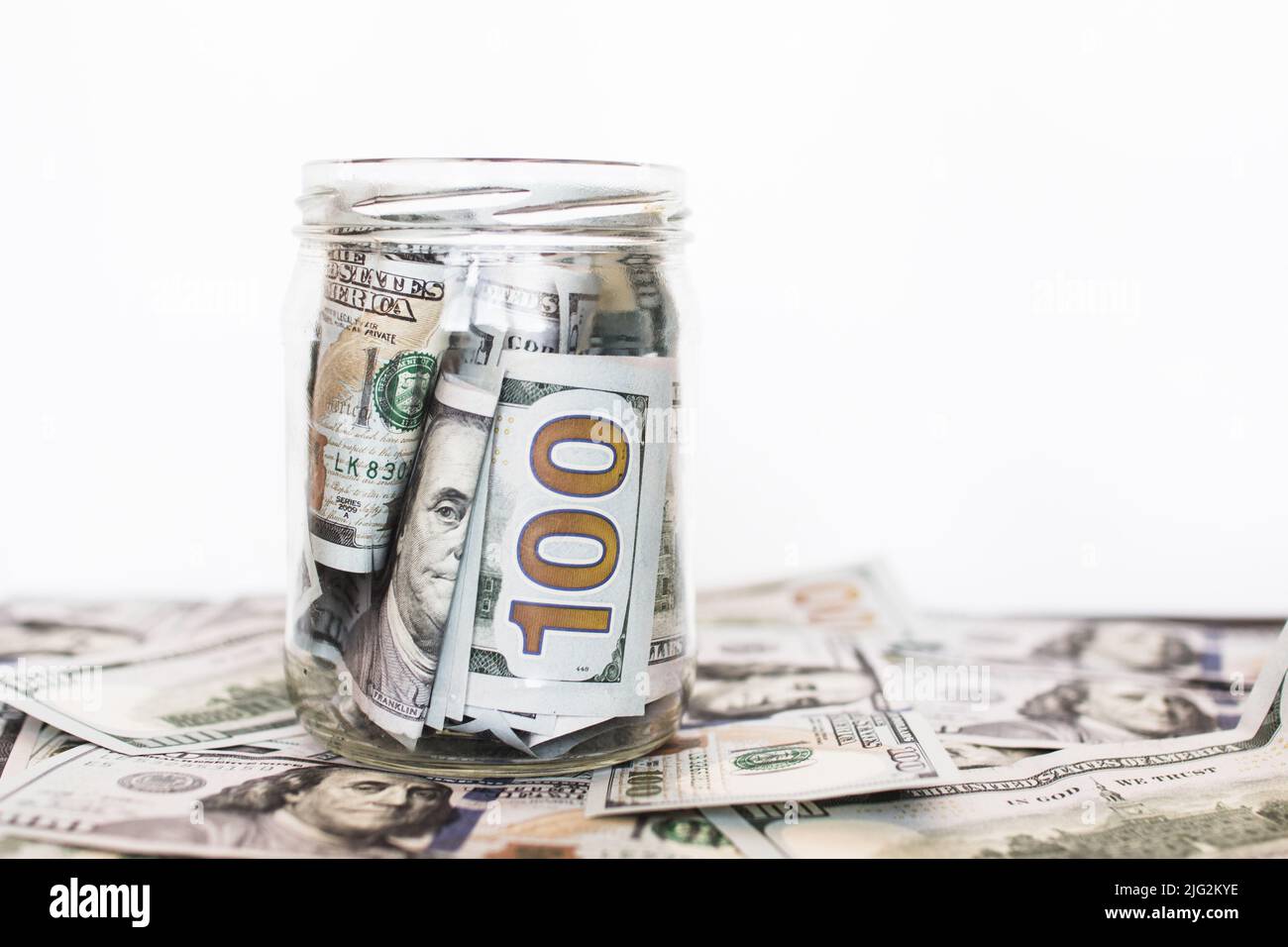 Glass jar with coins on the white background. A lot of dollar bills ...