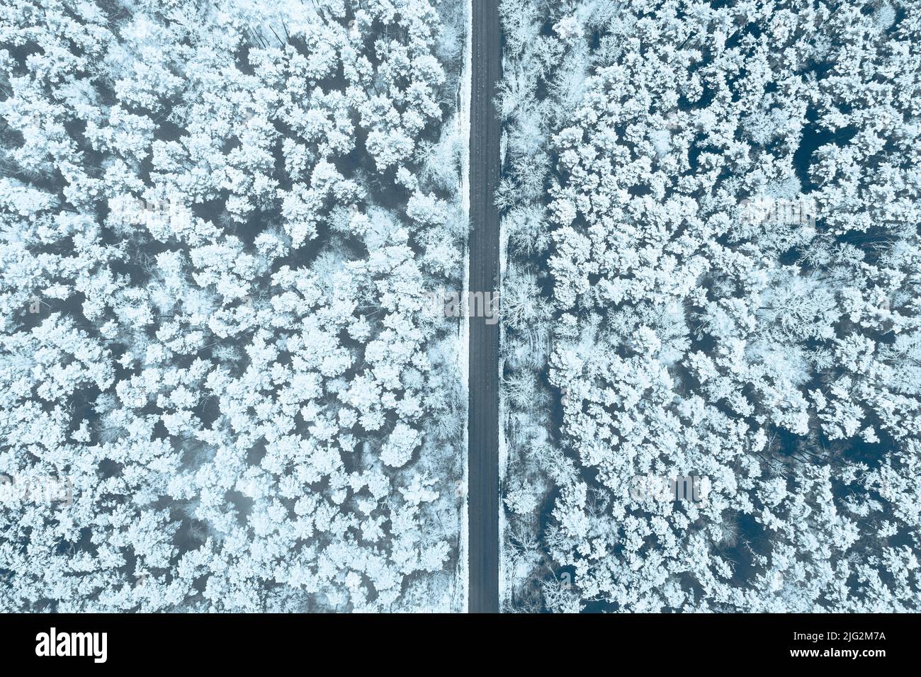 Aerial view of highway road through snow forest landscape in winter ...